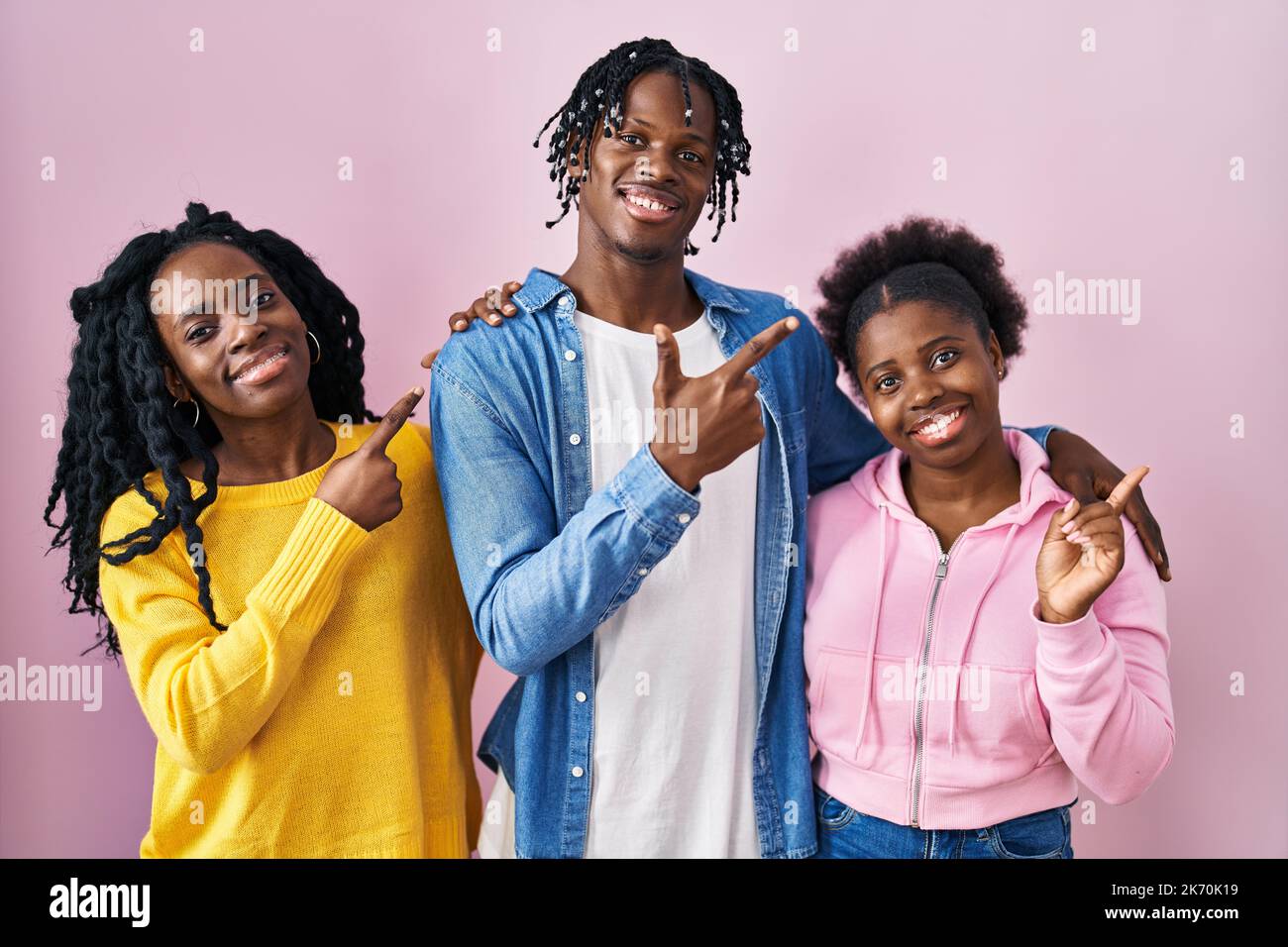 Group of three young black people standing together over pink ...