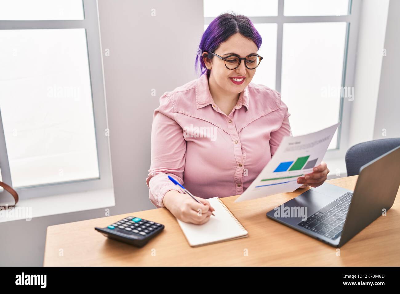 Young beautiful plus size woman business worker writing on notebook ...