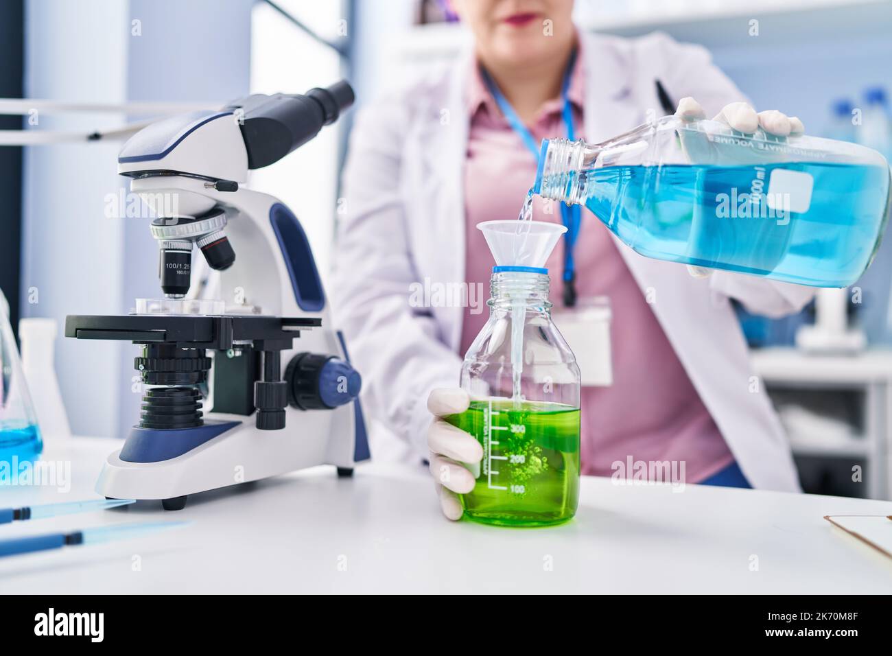 Young beautiful plus size woman scientist pouring liquid on test tube ...