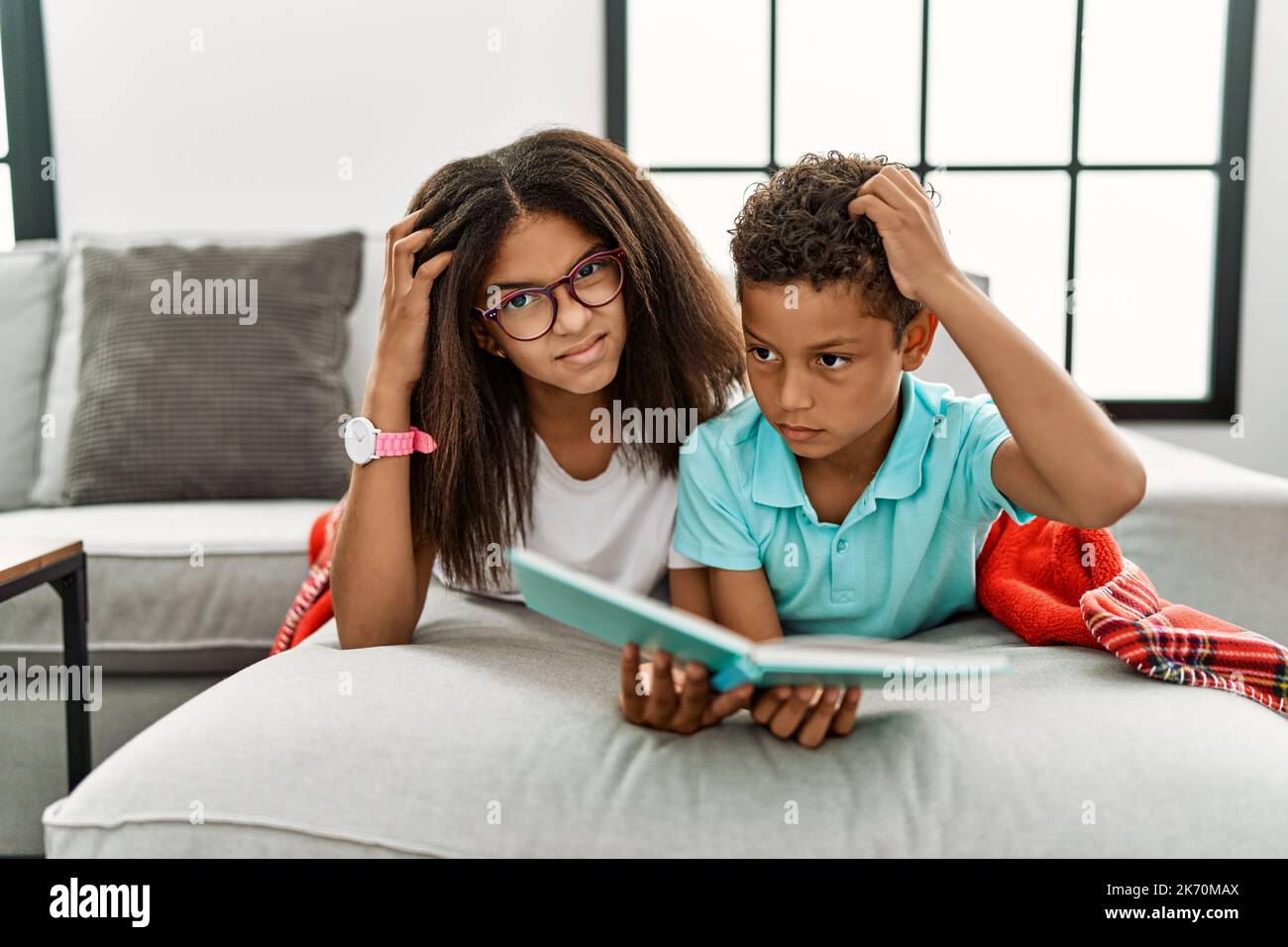 Two siblings lying on the sofa reading a book confuse and wondering ...
