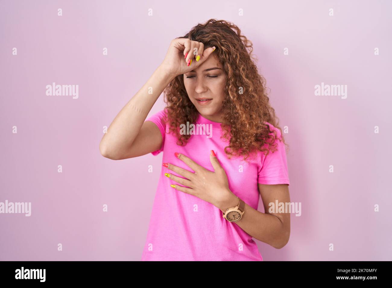 Young caucasian woman standing over pink background touching forehead ...