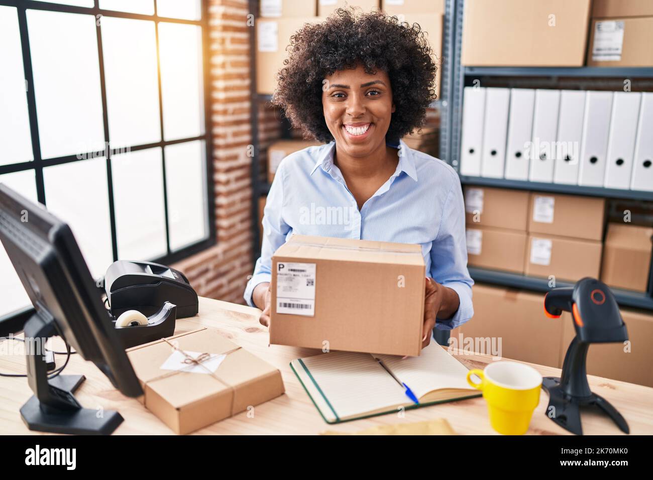Black woman with curly hair working at small business ecommerce holding ...