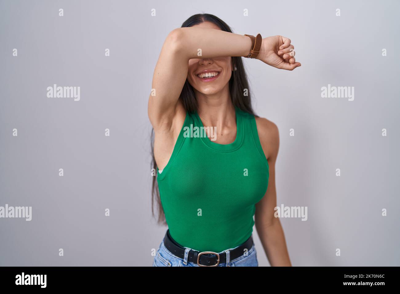 Young woman standing over isolated background covering eyes with arm ...