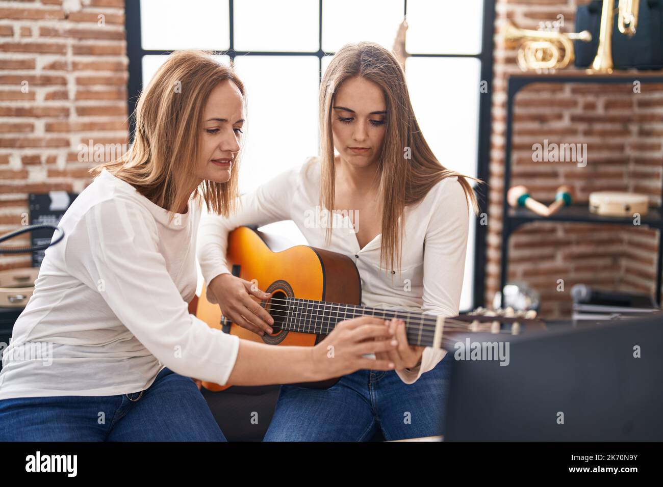 Two women musicians having classical guitar lesson at music studio ...