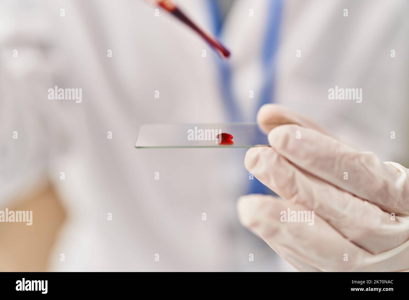 Young blonde woman wearing scientist uniform analysing blood at ...
