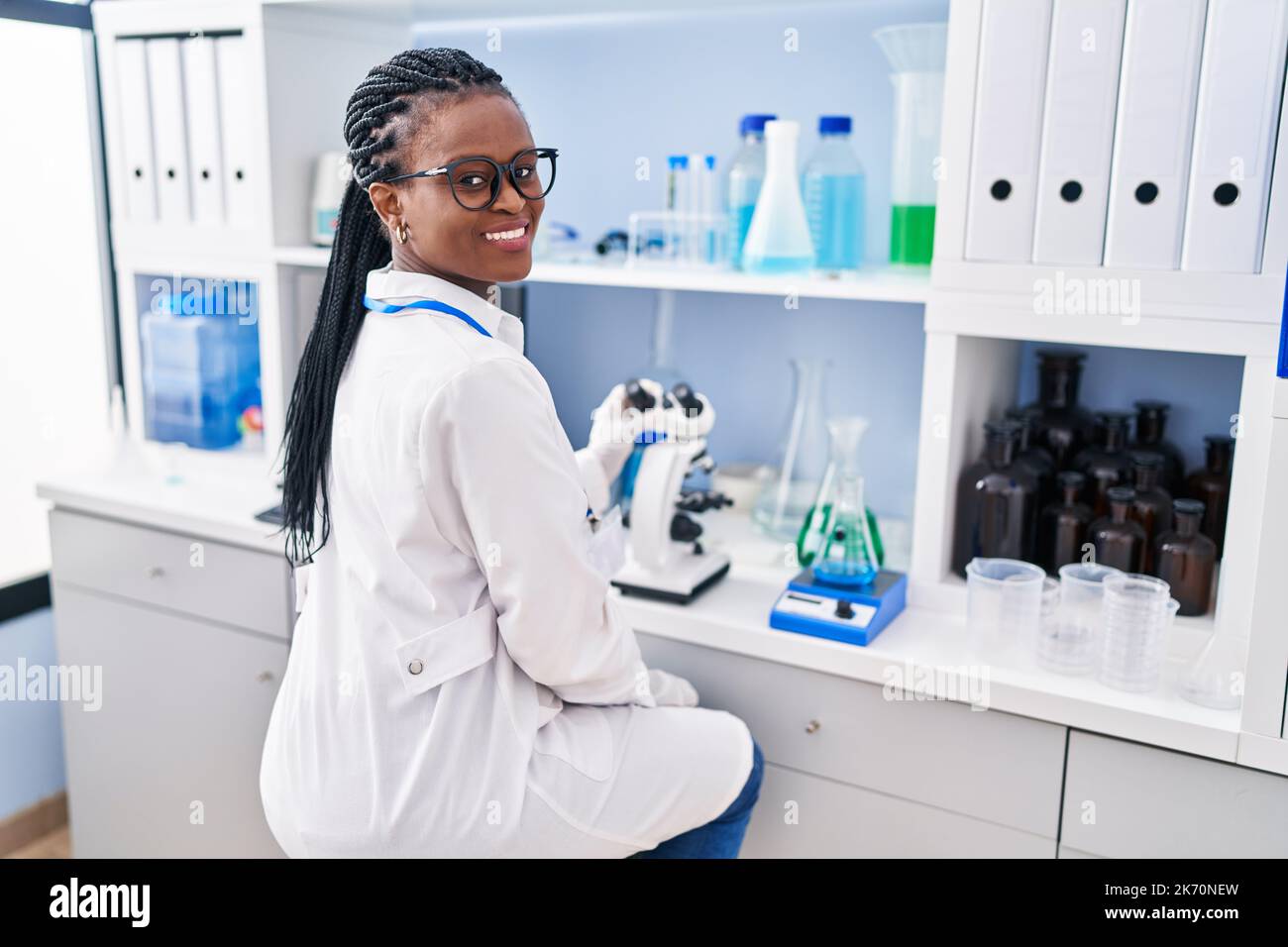 African american woman scientist smiling confident using microscope at laboratory Stock Photo ...
