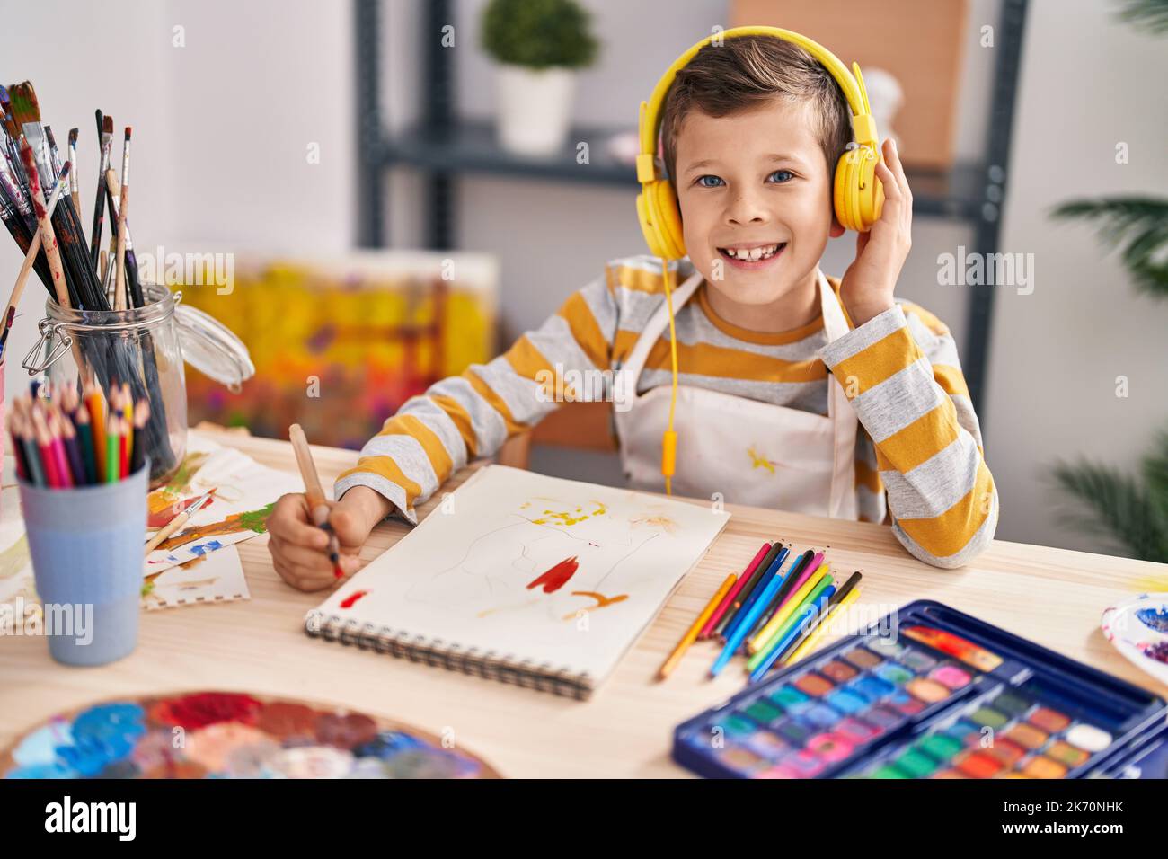 Blond child listening to music drawing at art studio Stock Photo - Alamy