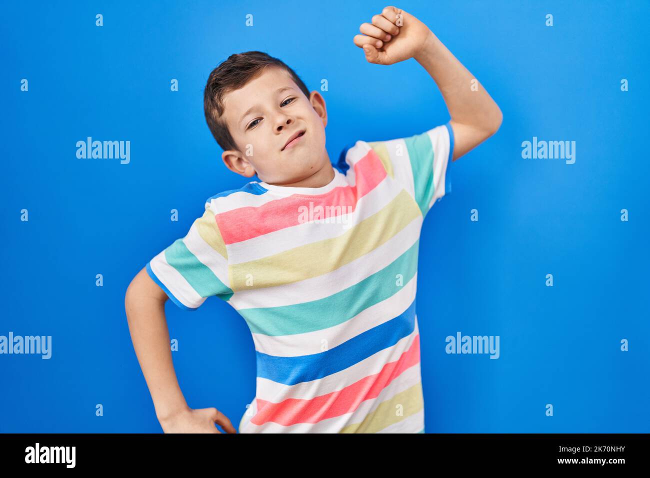 Young caucasian kid standing over blue background stretching back ...