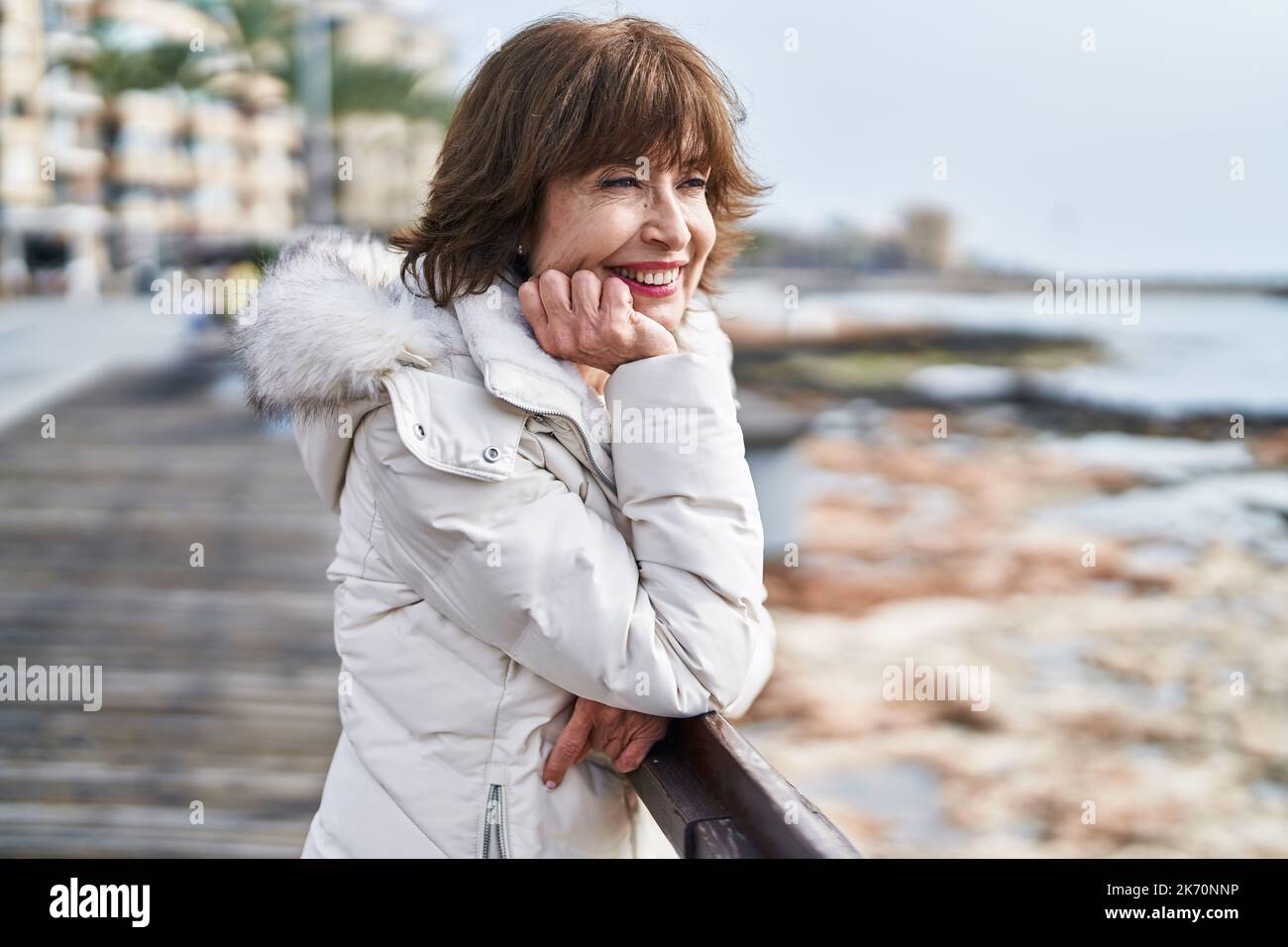 Middle age woman smiling confident leaning on balustrade at seaside ...