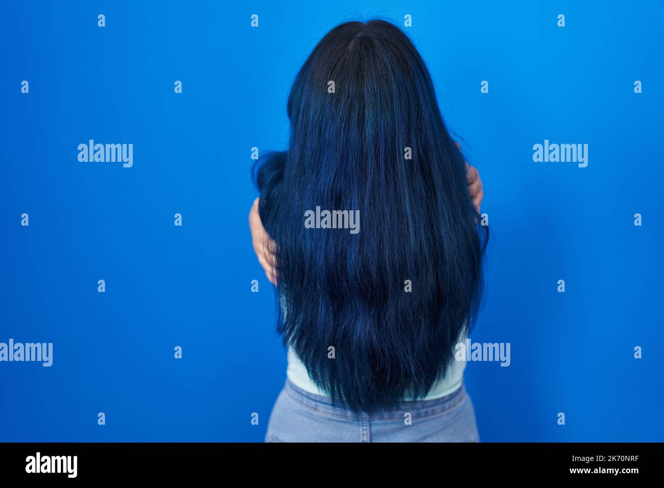 Young Modern Girl With Blue Hair Standing Over Blue Background Hugging 6158