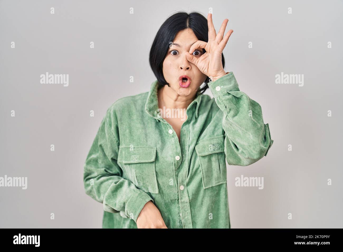 Young asian woman standing over white background doing ok gesture ...