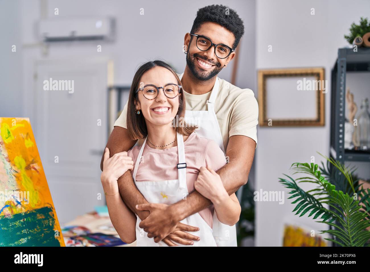 Man and woman artists smiling confident hugging each other at art ...