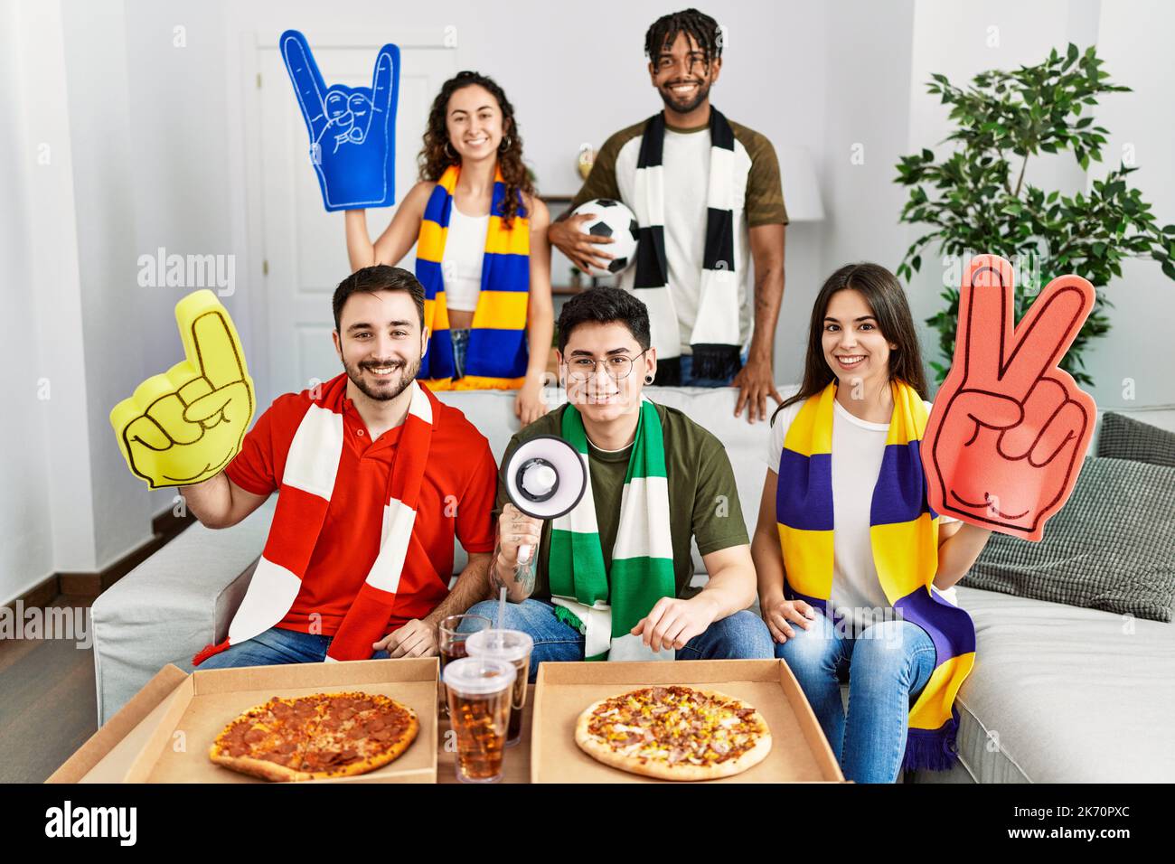 Group of young people wearing team scarf cheering football game looking ...