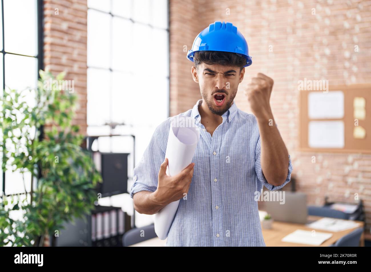 Arab man with beard wearing architect hardhat at construction office ...