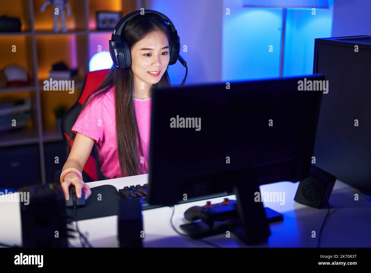 Young chinese woman streamer playing video game using computer at ...
