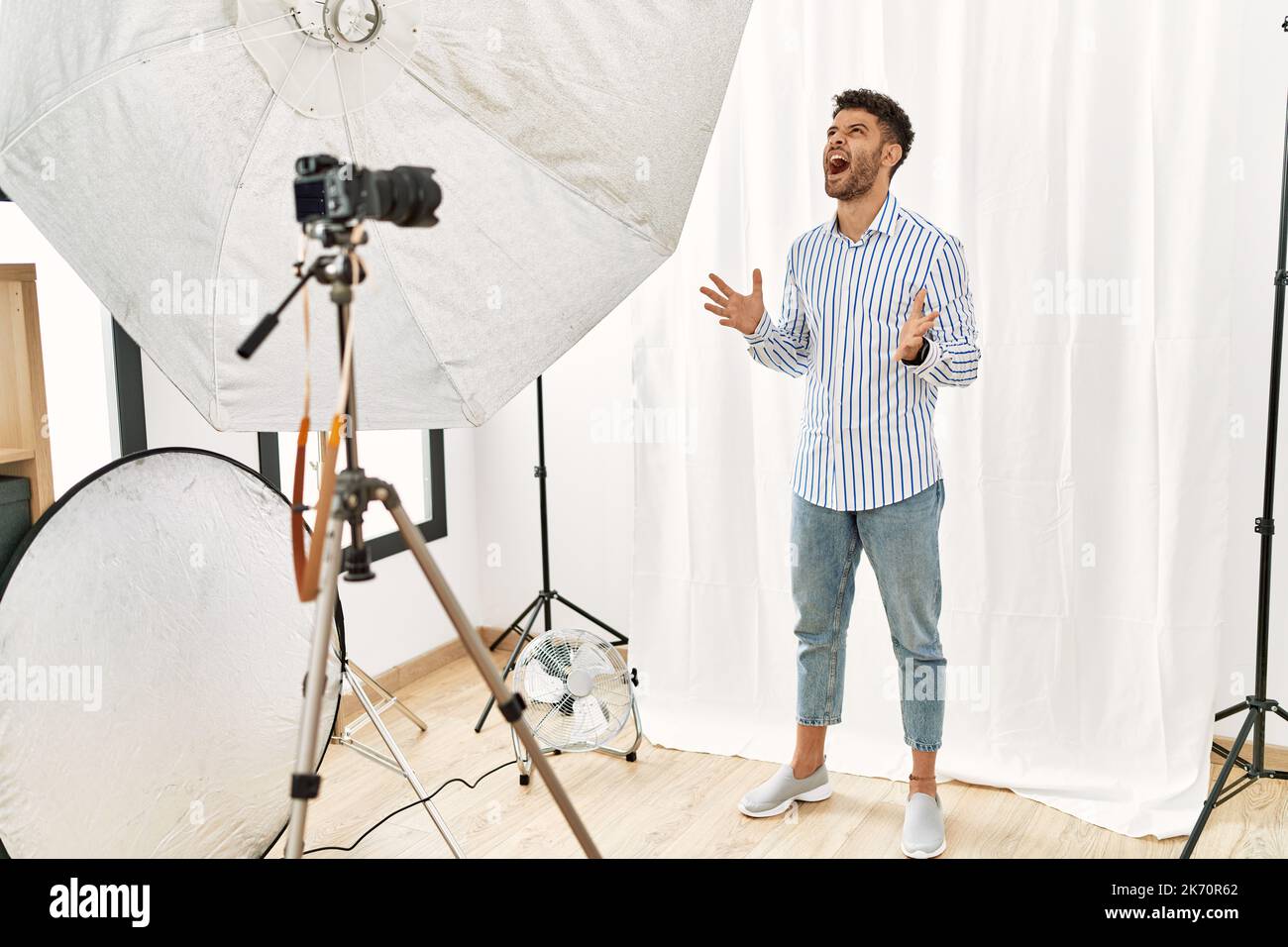 Arab young man posing as model at photography studio crazy and mad shouting and yelling with ...