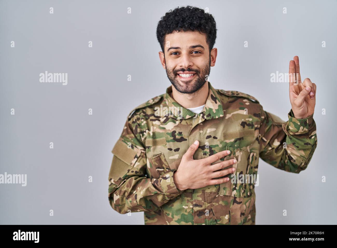 Arab man wearing camouflage army uniform smiling swearing with hand on ...