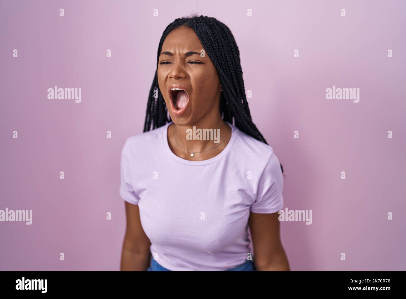 African american woman with braids standing over pink background angry ...