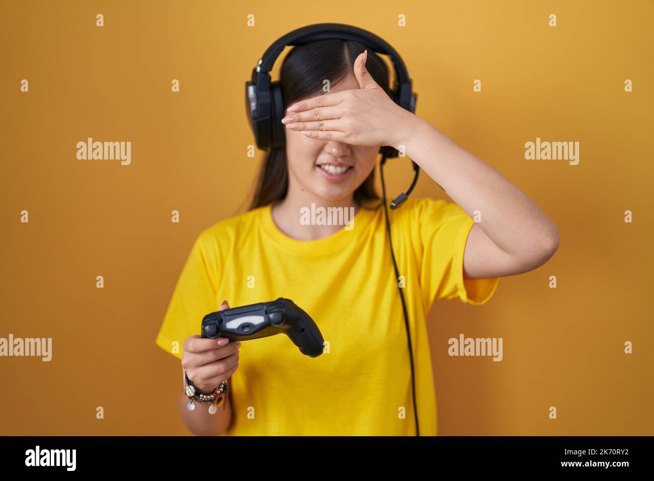 Chinese young woman playing video game holding controller smiling and ...