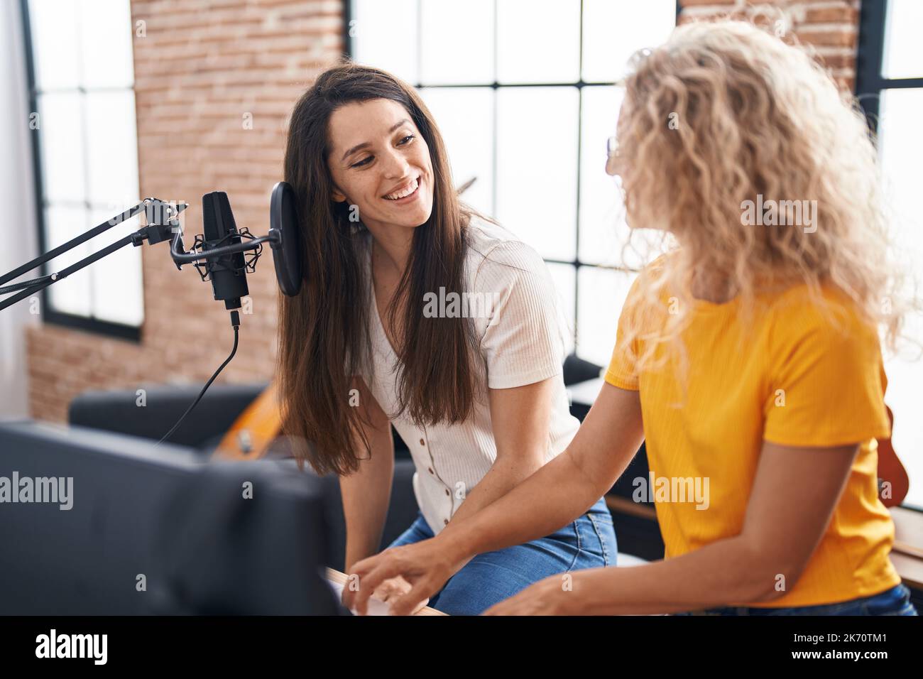 Two women musicians singing song playing piano keyboard at music studio ...