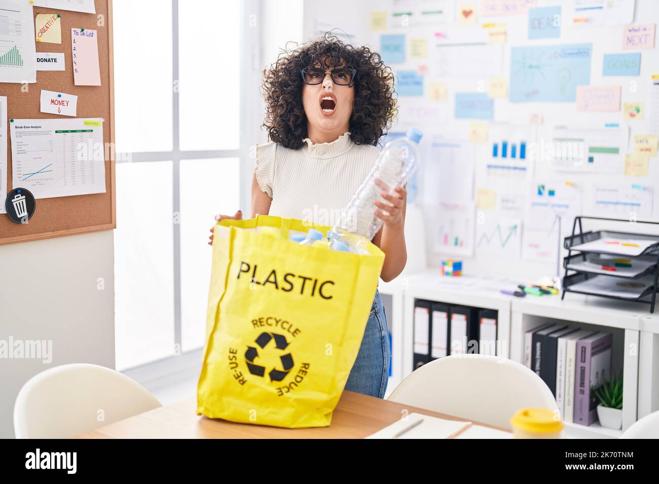 Young middle east woman holding recycling bag with plastic bottles at ...