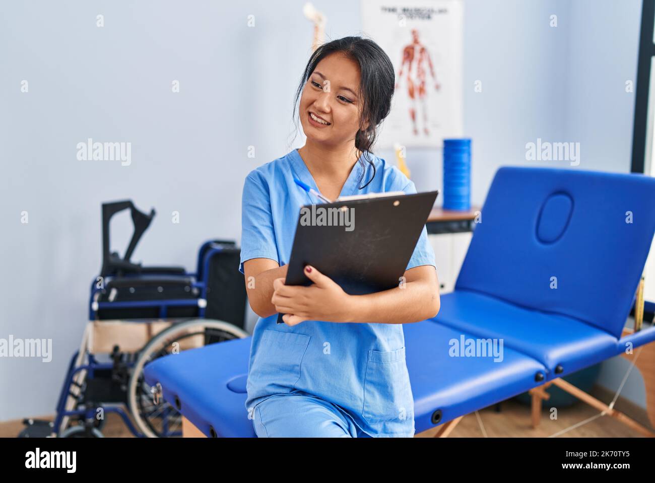 Young chinese woman wearing physiotherapist uniform write on medical ...