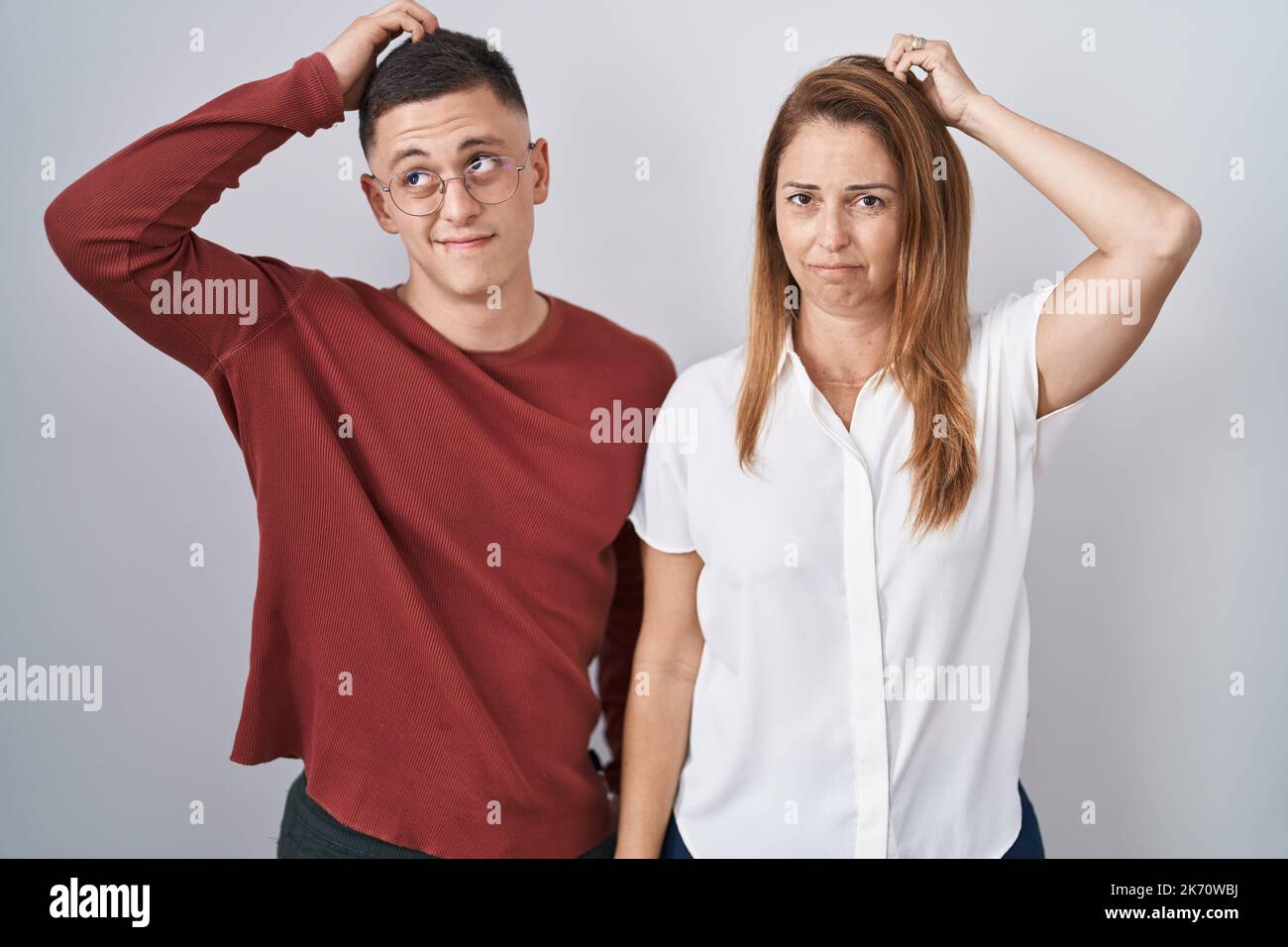 Mother and son standing together over isolated background confuse and ...