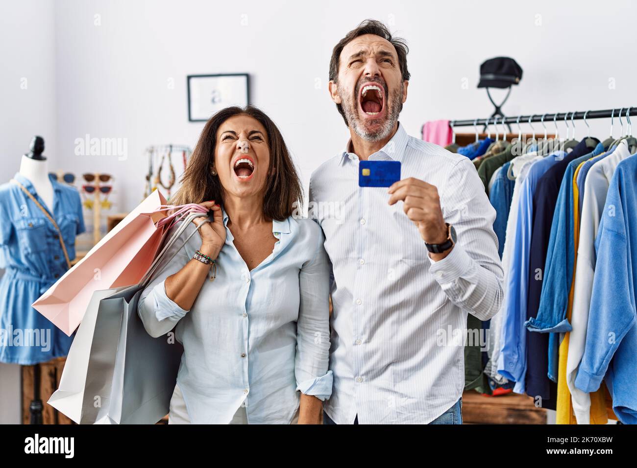 Hispanic middle age couple holding shopping bags and credit card angry ...