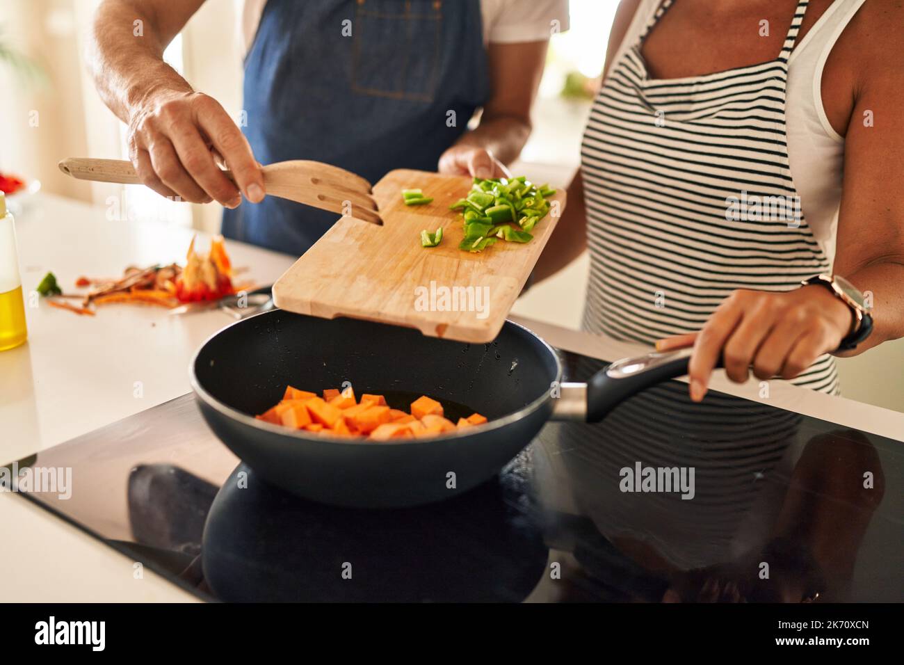Middle age hispanic couple pouring food on frying pan at kitchen Stock ...