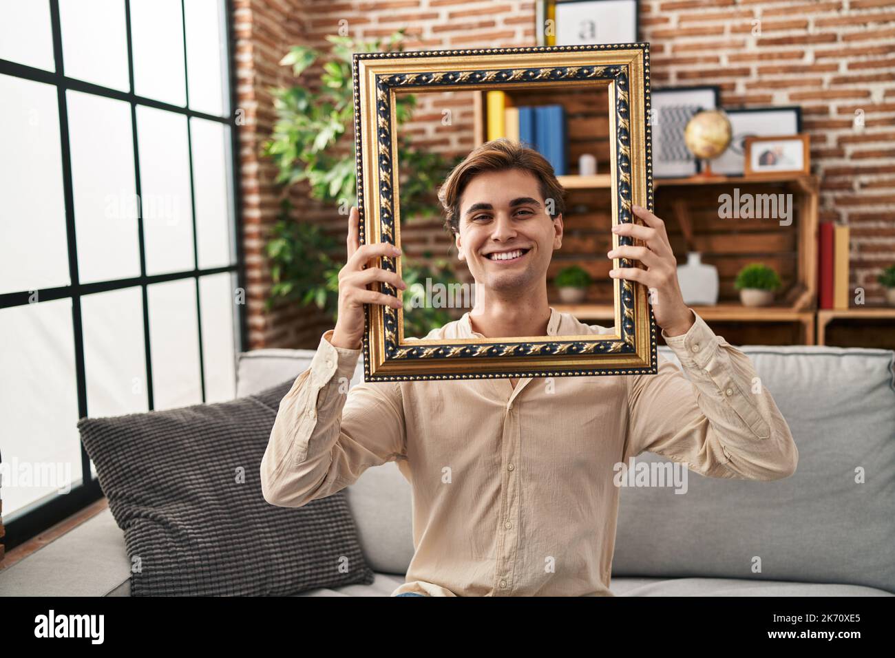 Young man holding empty frame smiling with a happy and cool smile on ...