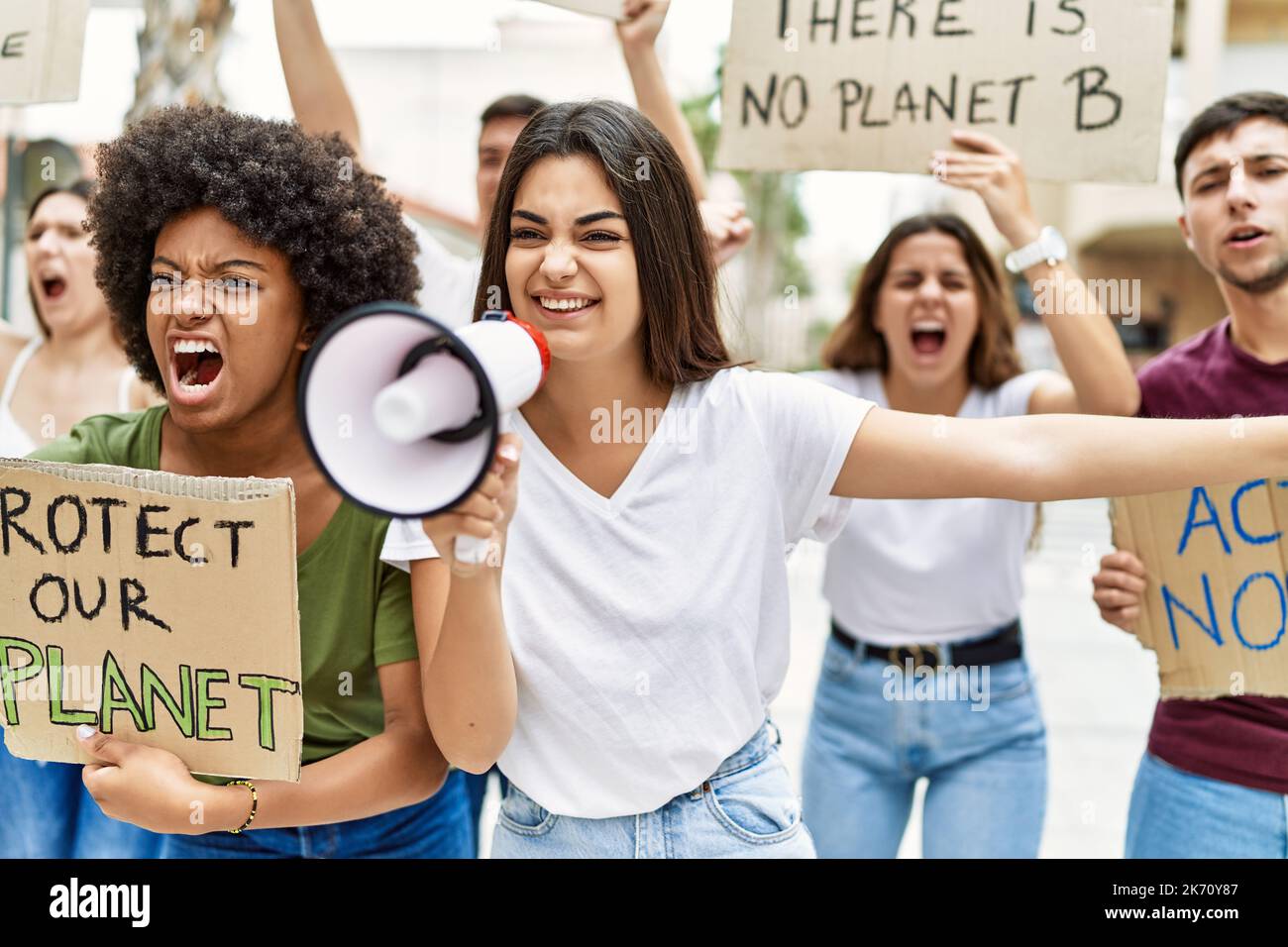 Group of young activists people protesting holding banner and using ...