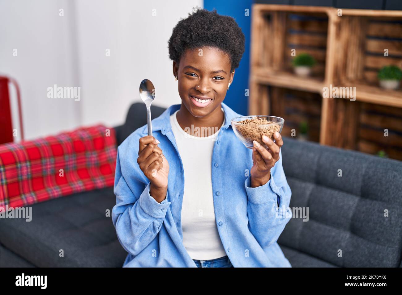 African american woman eating healthy whole grain cereals smiling with ...