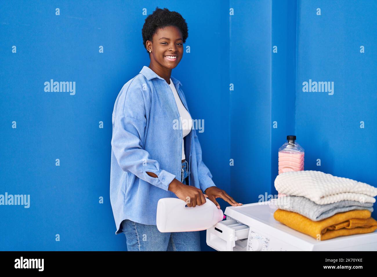 African american woman smiling confident pouring detergent on washing ...
