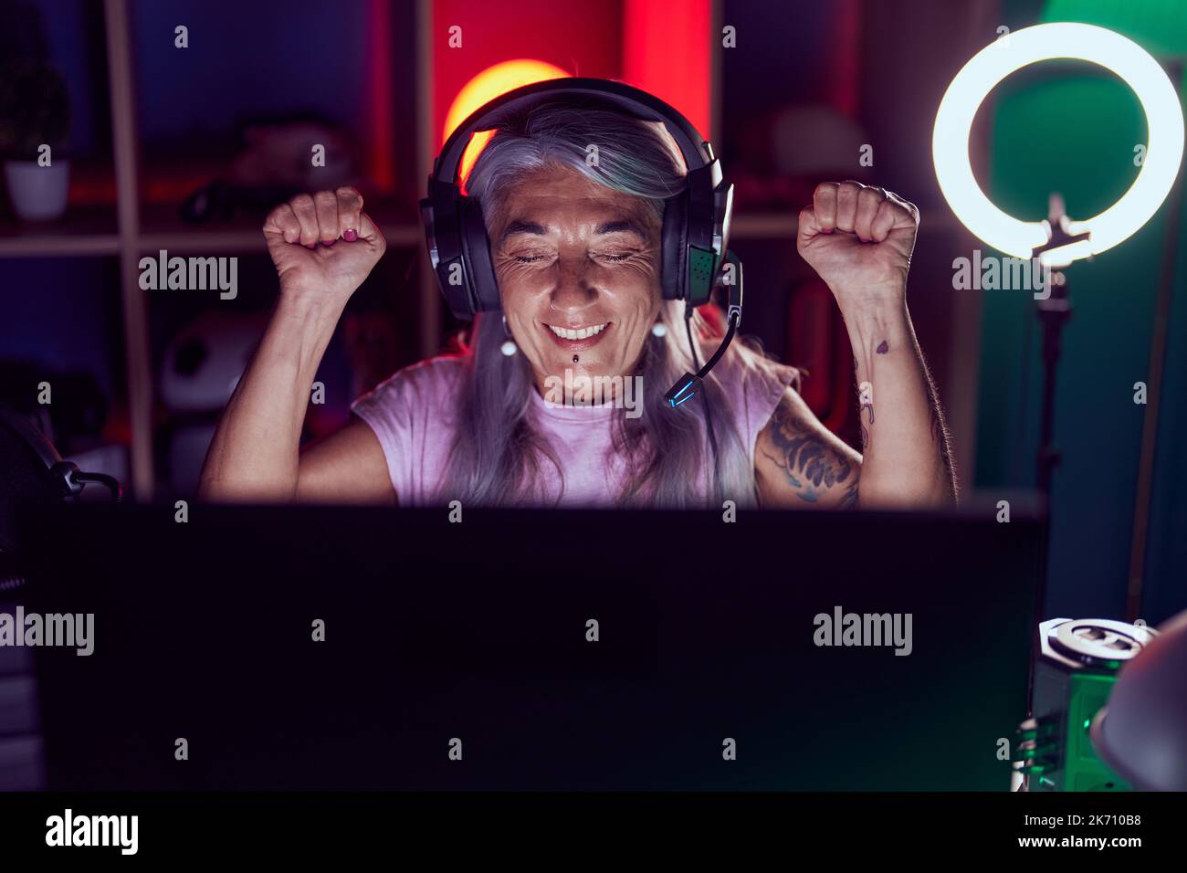 Middle age grey-haired woman streamer playing video game with winner ...