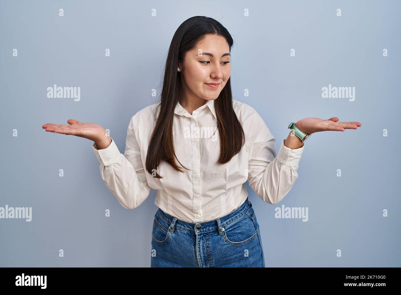 Young latin woman standing over blue background smiling showing both ...