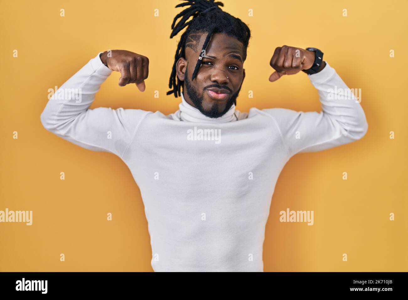 African man with dreadlocks wearing turtleneck sweater over yellow ...