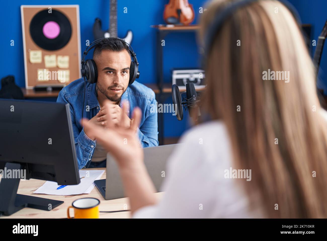 Man and woman musicians listening to music speaking at music studio ...
