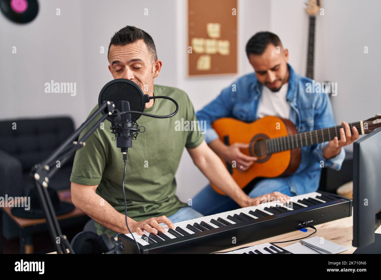 Two men musicians singing song playing piano and classical guitar at ...