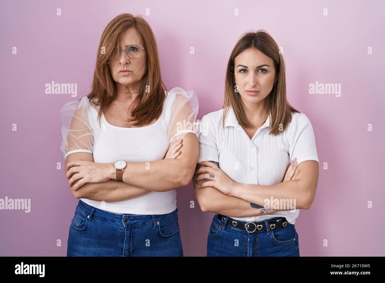 Hispanic mother and daughter wearing casual white t shirt over pink ...