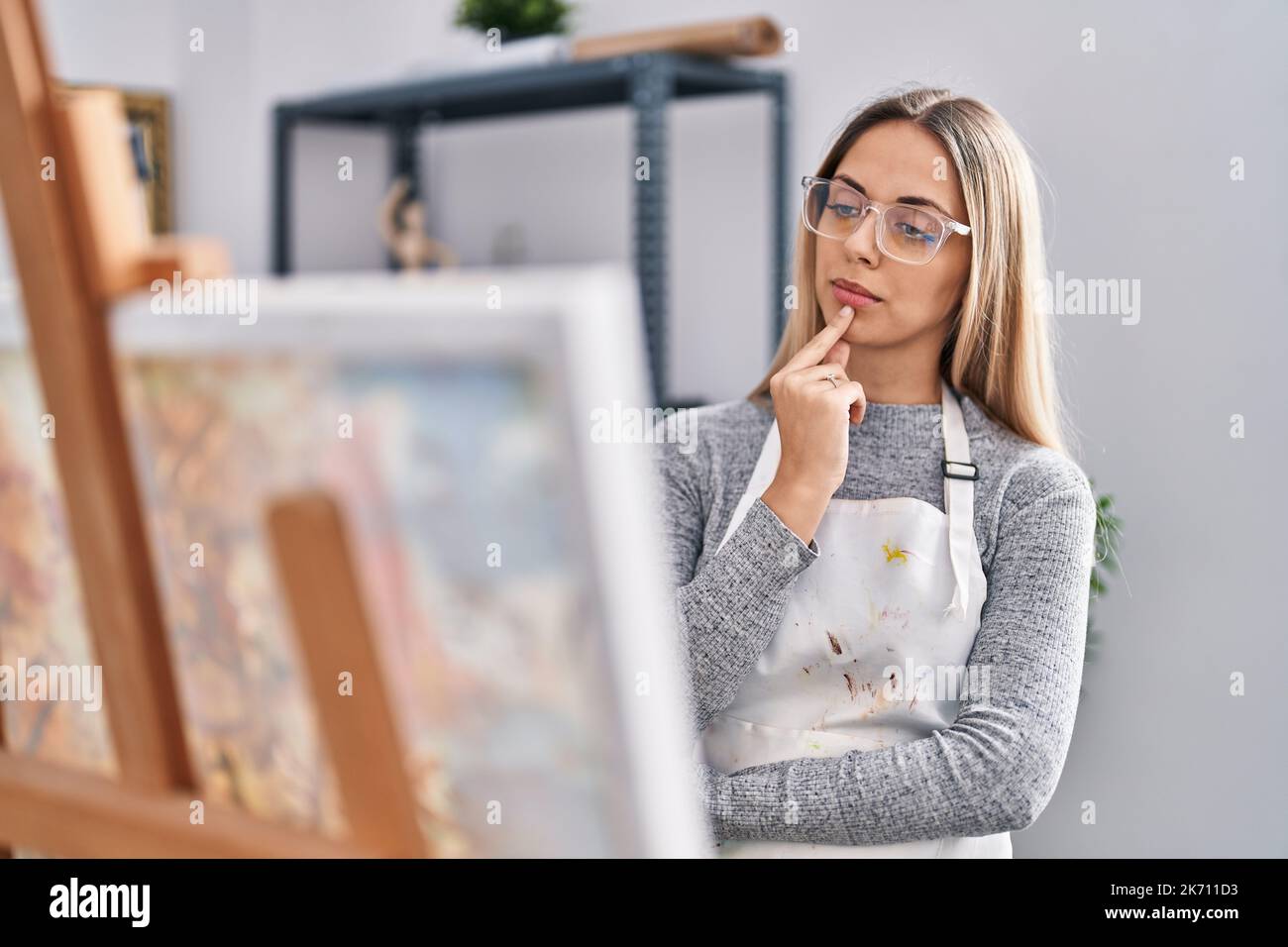 Young woman artist looking draw with doubt expression at art studio ...