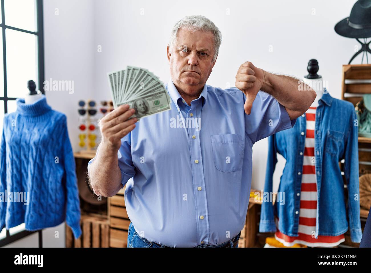 Senior man with grey hair holding dollars banknotes at retail shop with ...