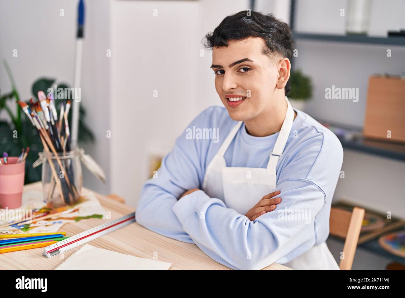 Young non binary man artist smiling confident sitting with arms crossed ...