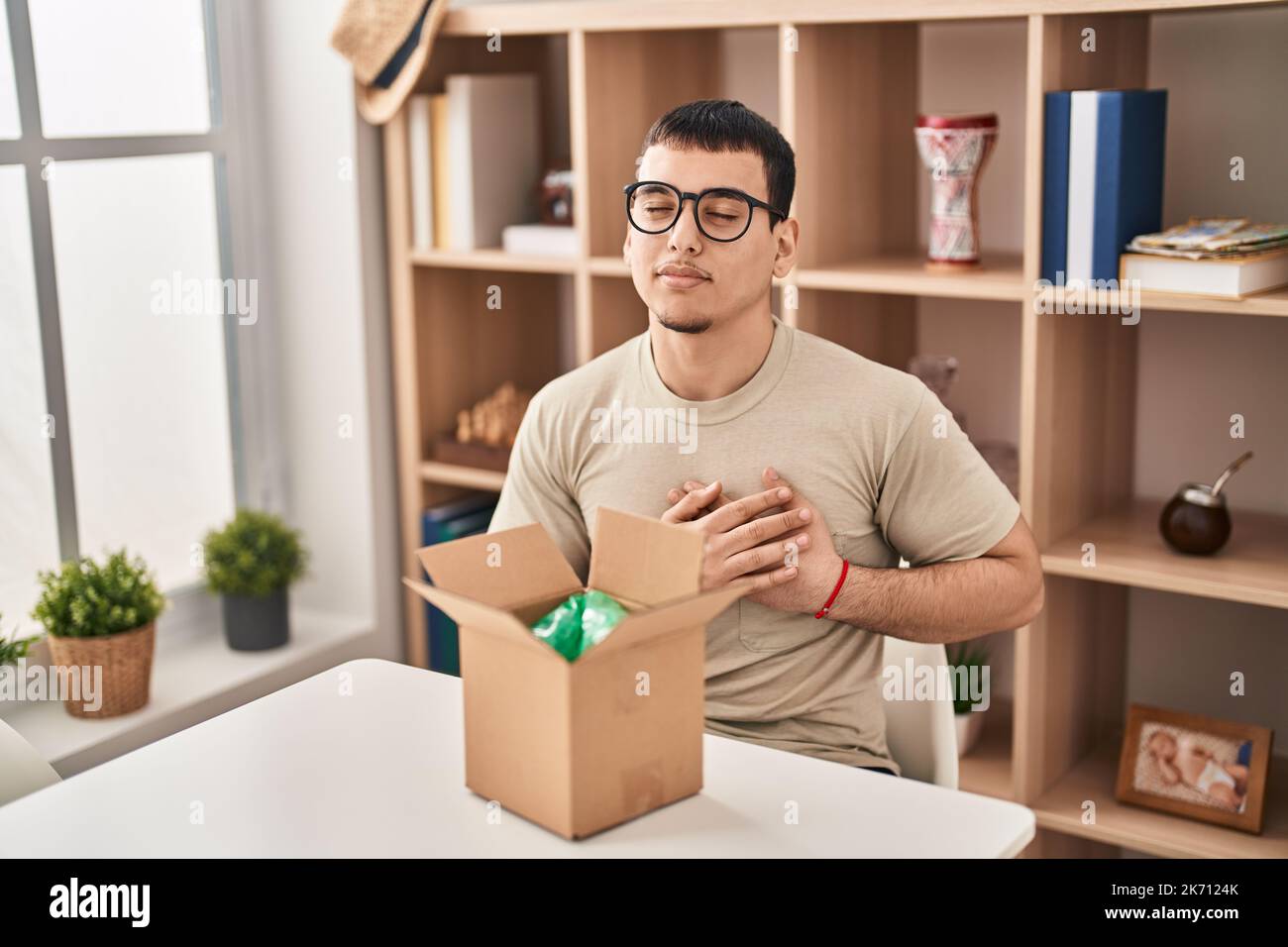 Young arab man with open gift in cardboard box smiling with hands on ...