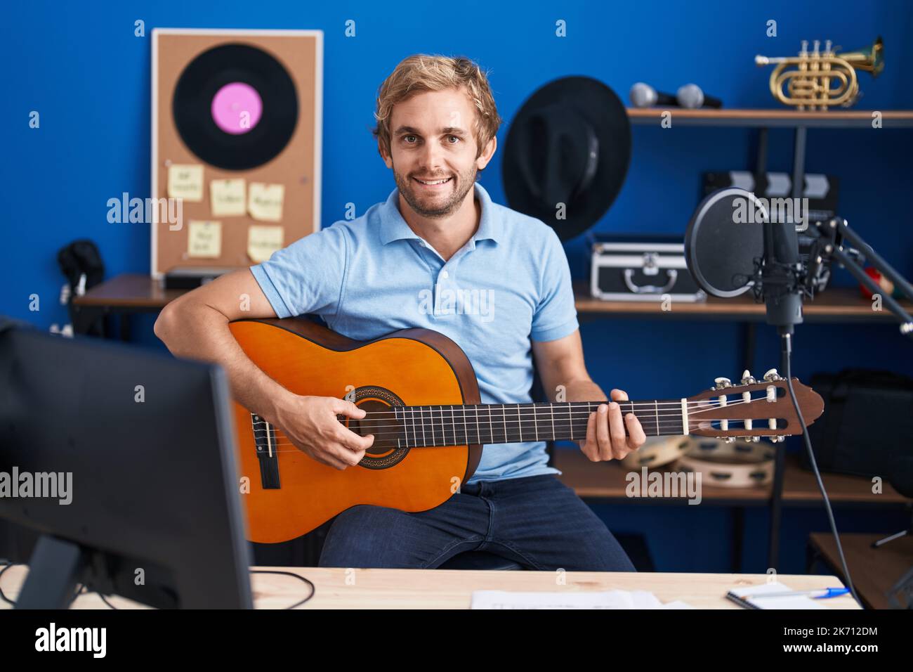 Caucasian man playing classic guitar at music studio smiling with a ...