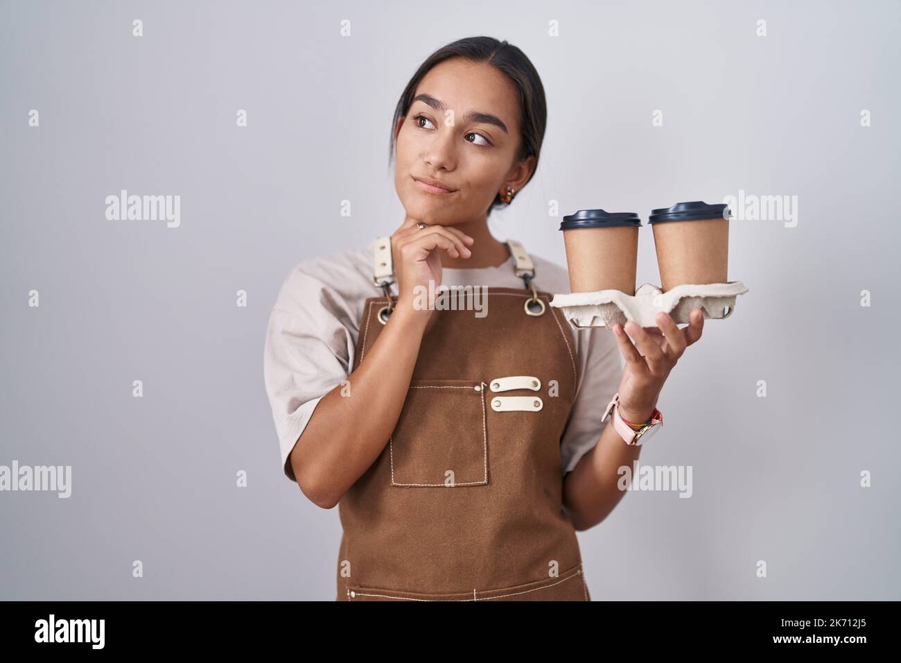 Young hispanic woman wearing professional waitress apron holding coffee ...