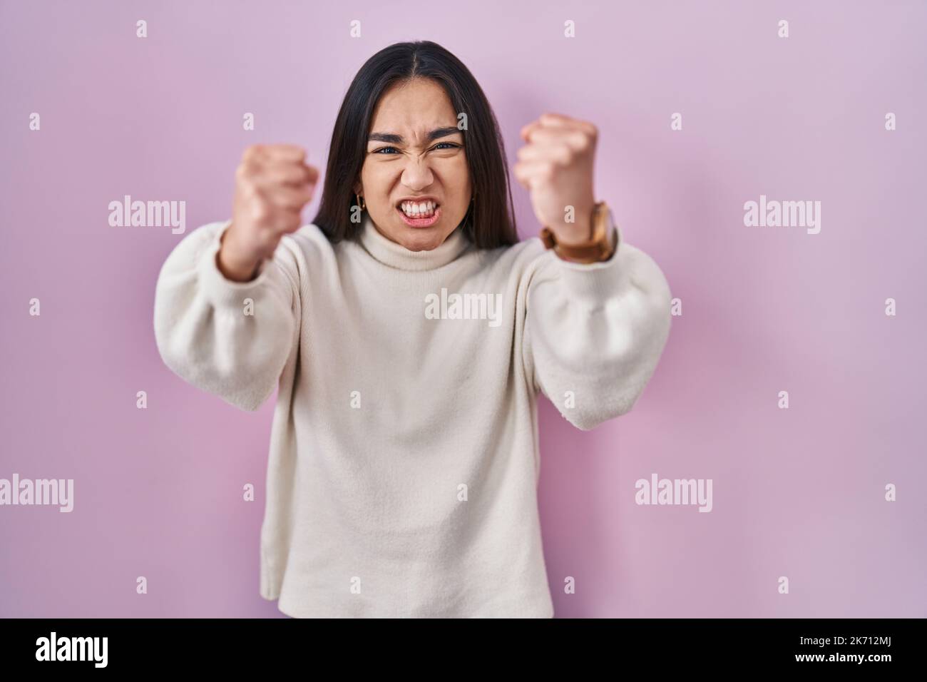 Young south asian woman standing over pink background angry and mad ...