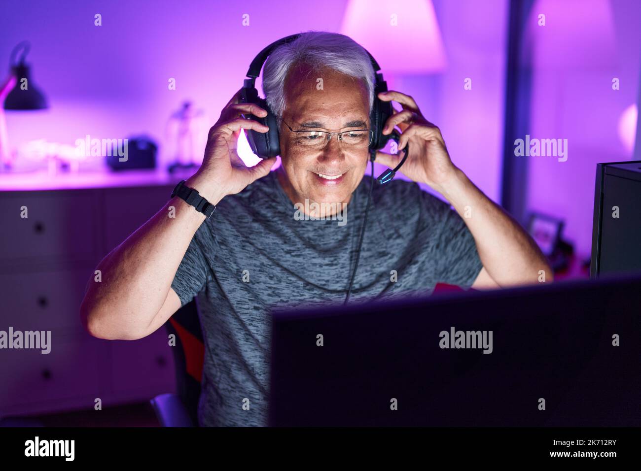 Middle age grey-haired man streamer playing video game using computer ...