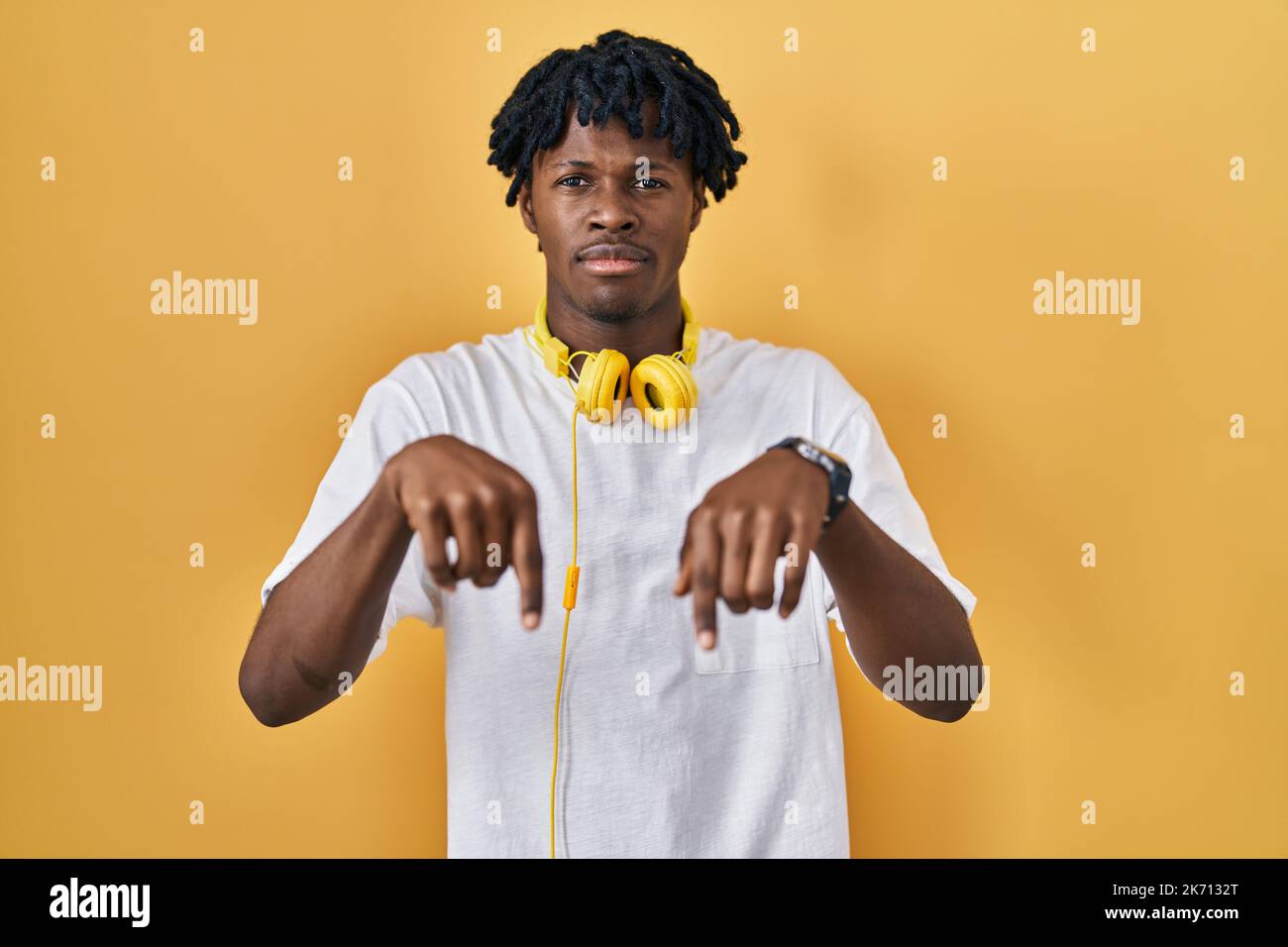 Young african man with dreadlocks standing over yellow background ...