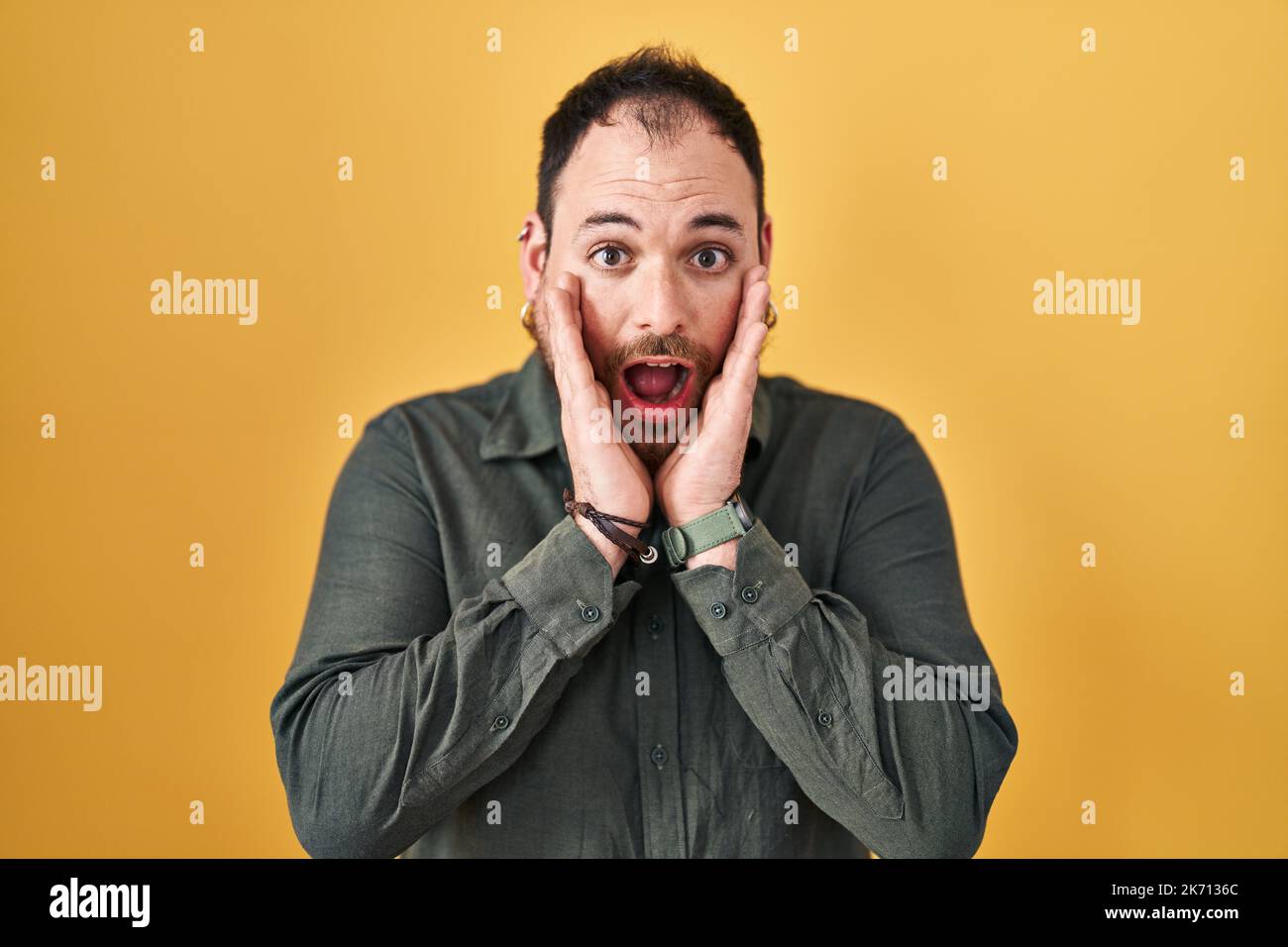 Plus size hispanic man with beard standing over yellow background ...