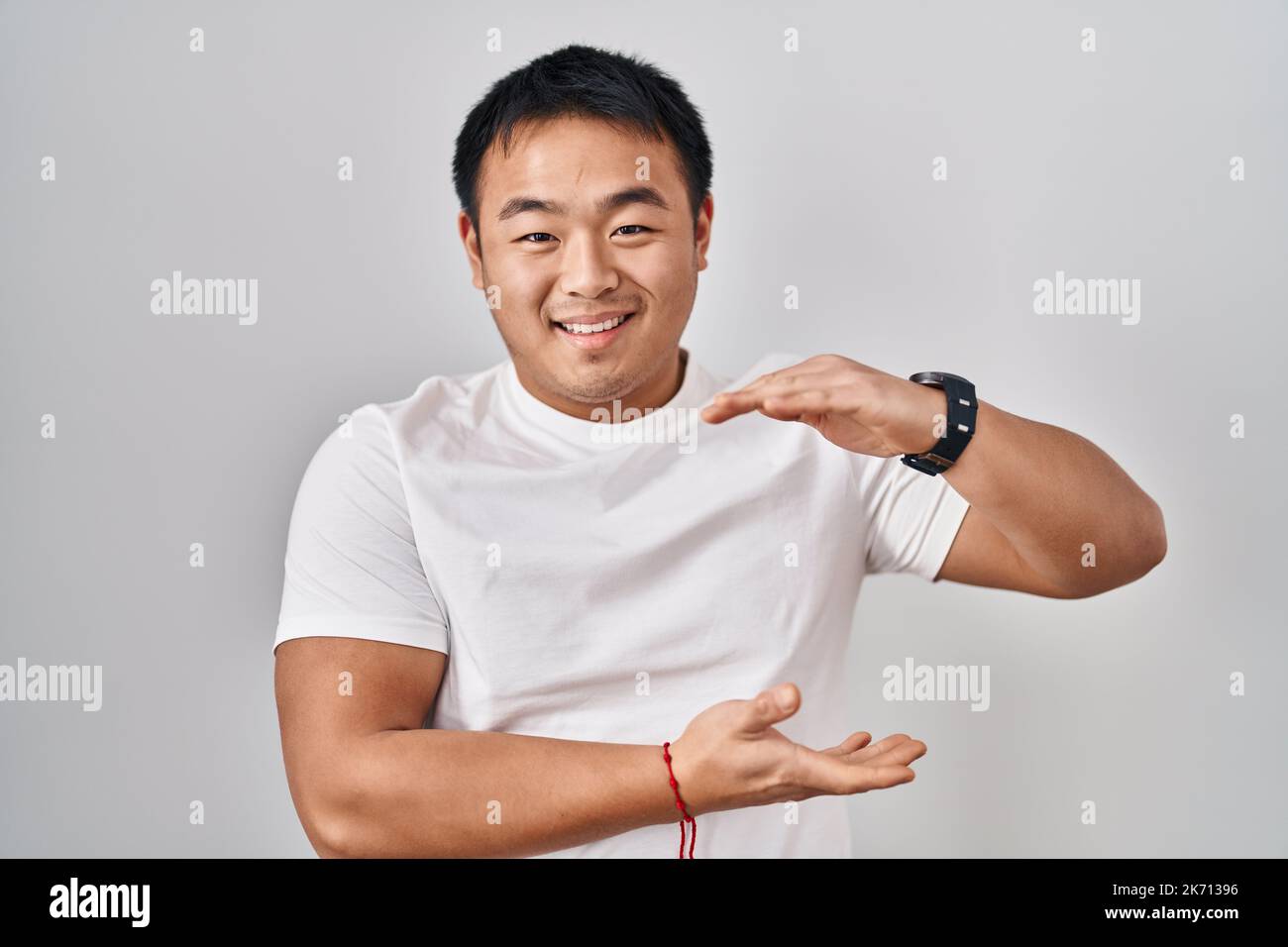 Young chinese man standing over white background gesturing with hands ...